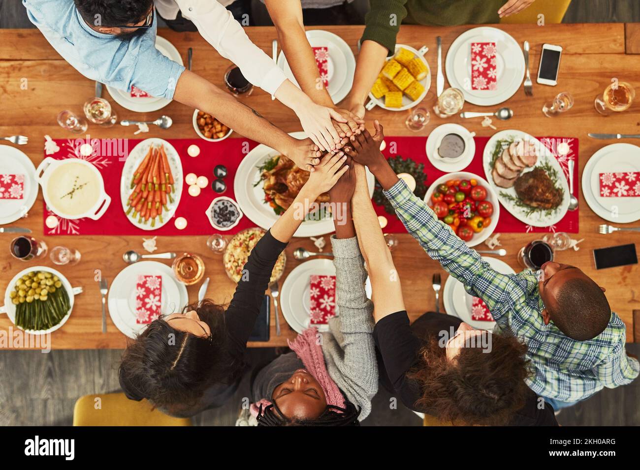 Christmas, high five and food with a group of friends sitting around a ...