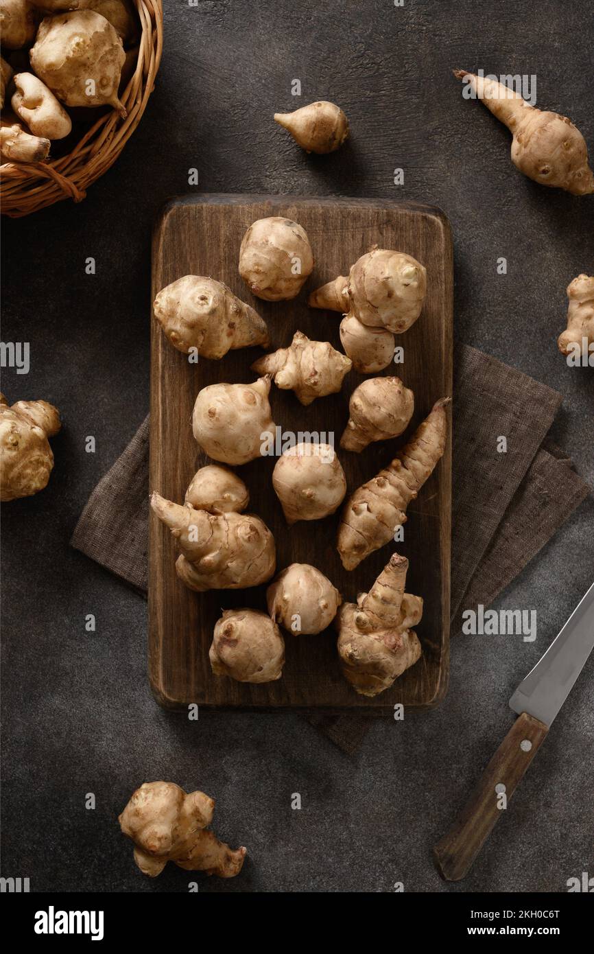 Cooking Jerusalem artichoke root, sunchoke on wooden cutting board. Top ...