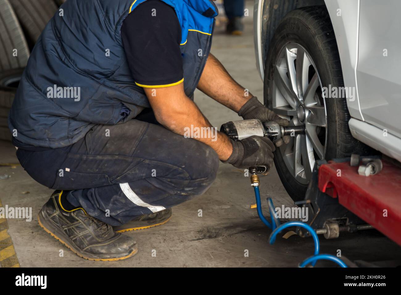 Auto mechanic man with electric screwdriver changing tire outside. Car ...