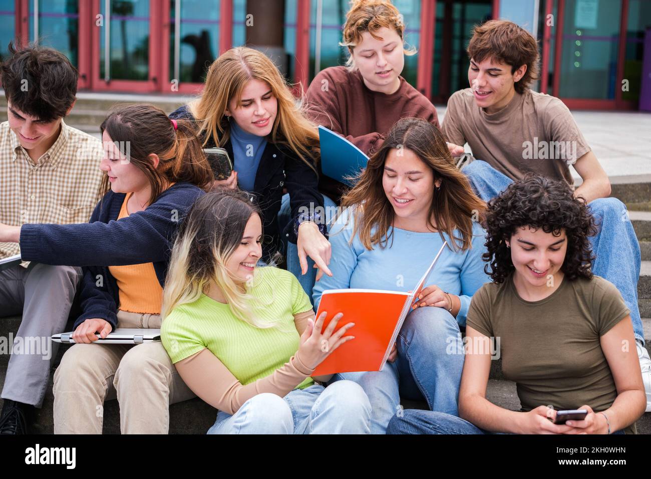 Group of college students sharing books and notes together at the door ...