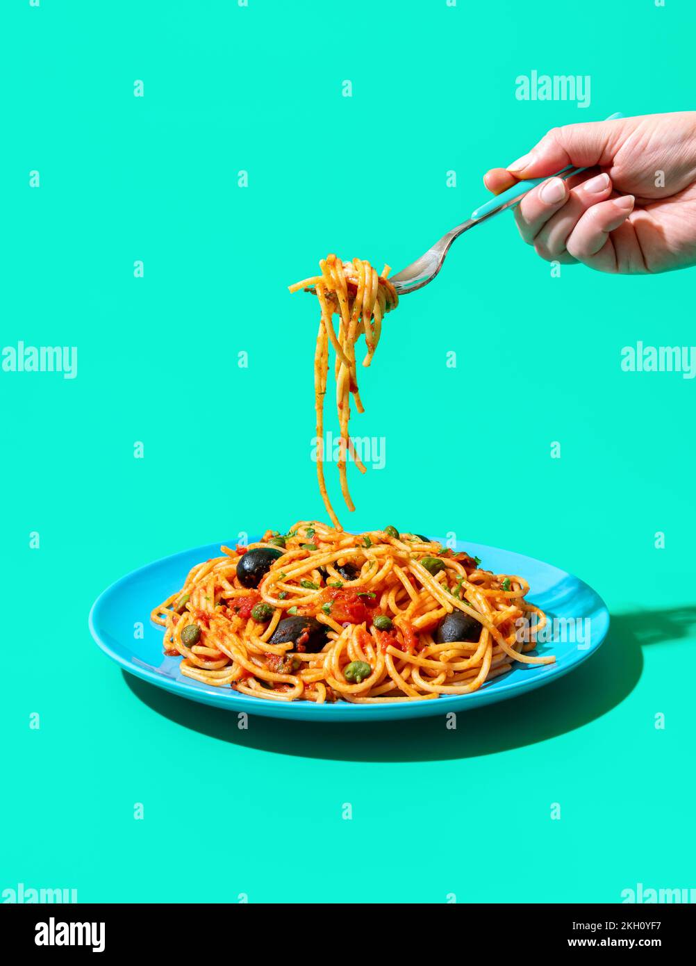 Woman's hand taking spaghetti from a plate using a fork, minimalist on ...