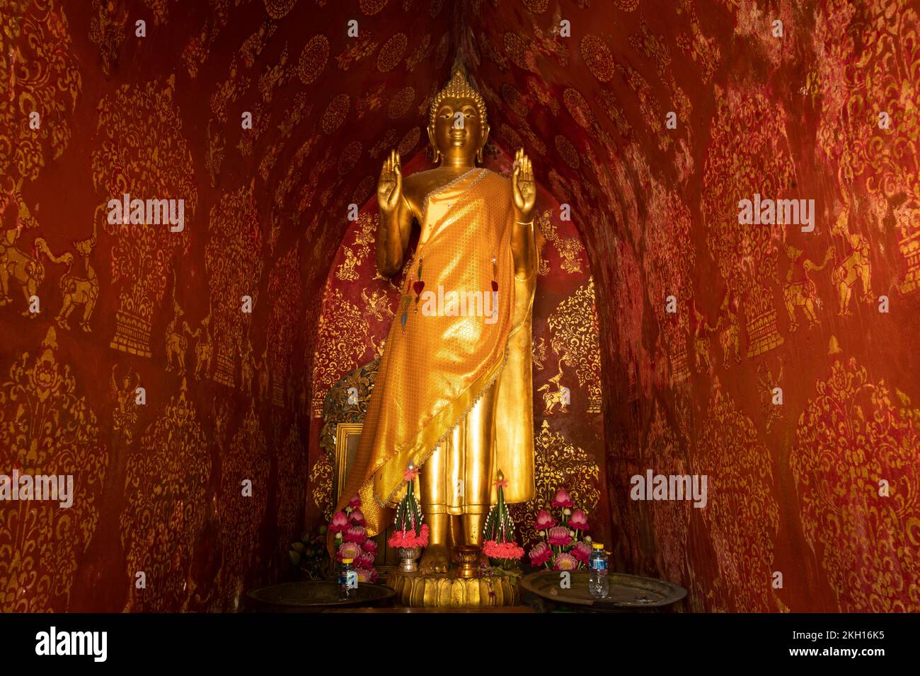 Golden statue of a standing Buddha performing the abhayamudra gesture ...