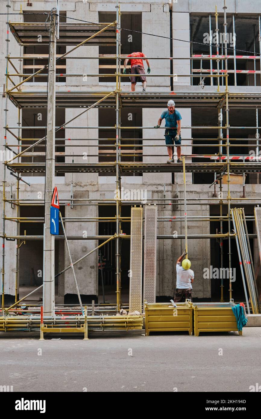A vertical shot of a building with construction scaffolding and people ...