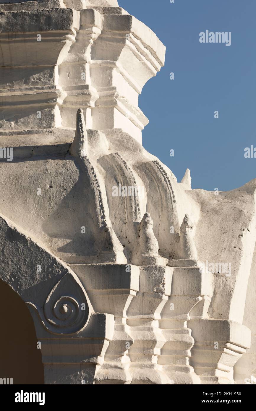 An ancient stupa painted in white, part of the opening of a gateway to ...