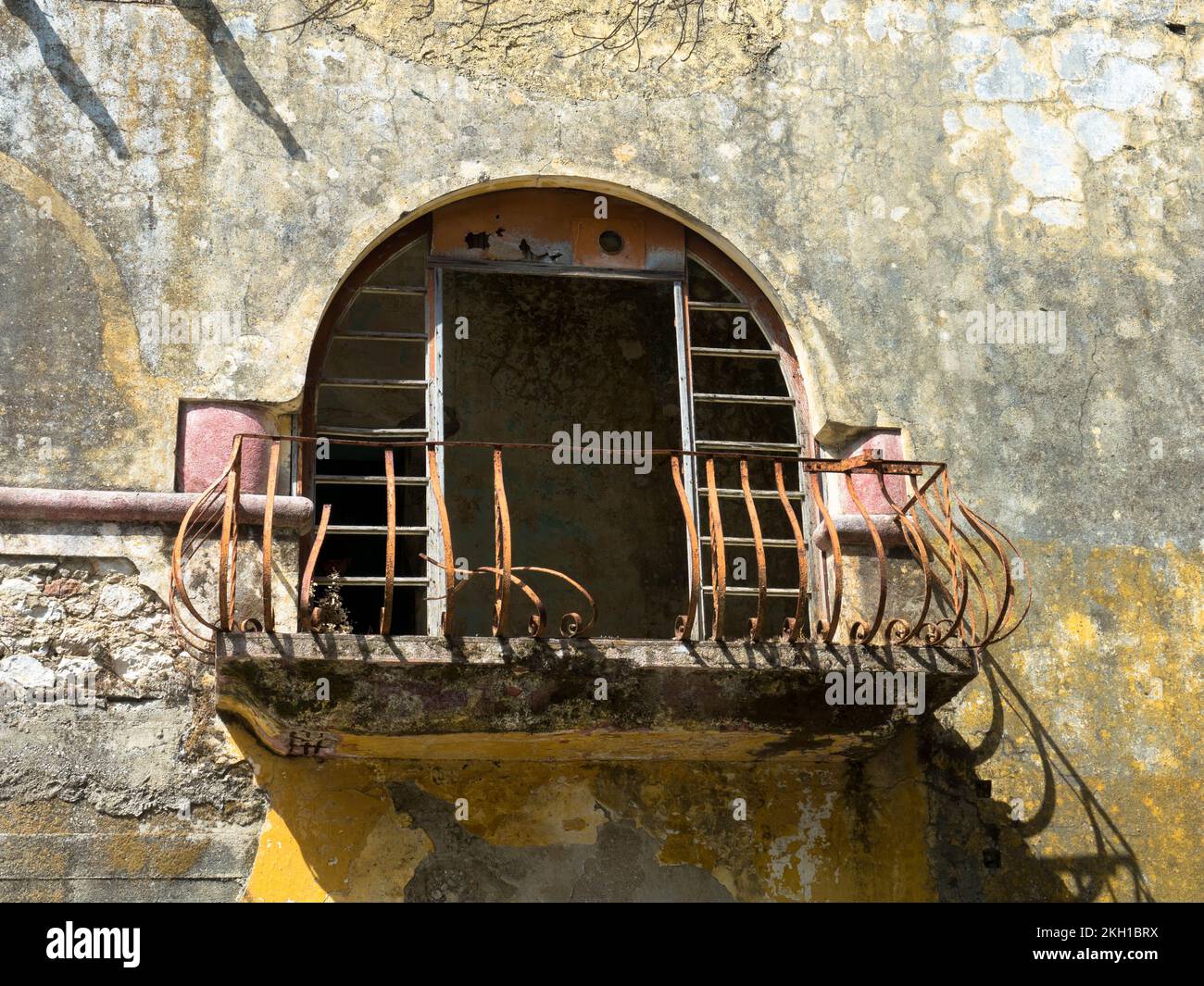 Lost Place in Eleousa. Detail view of an old rusty balcony. Village on ...