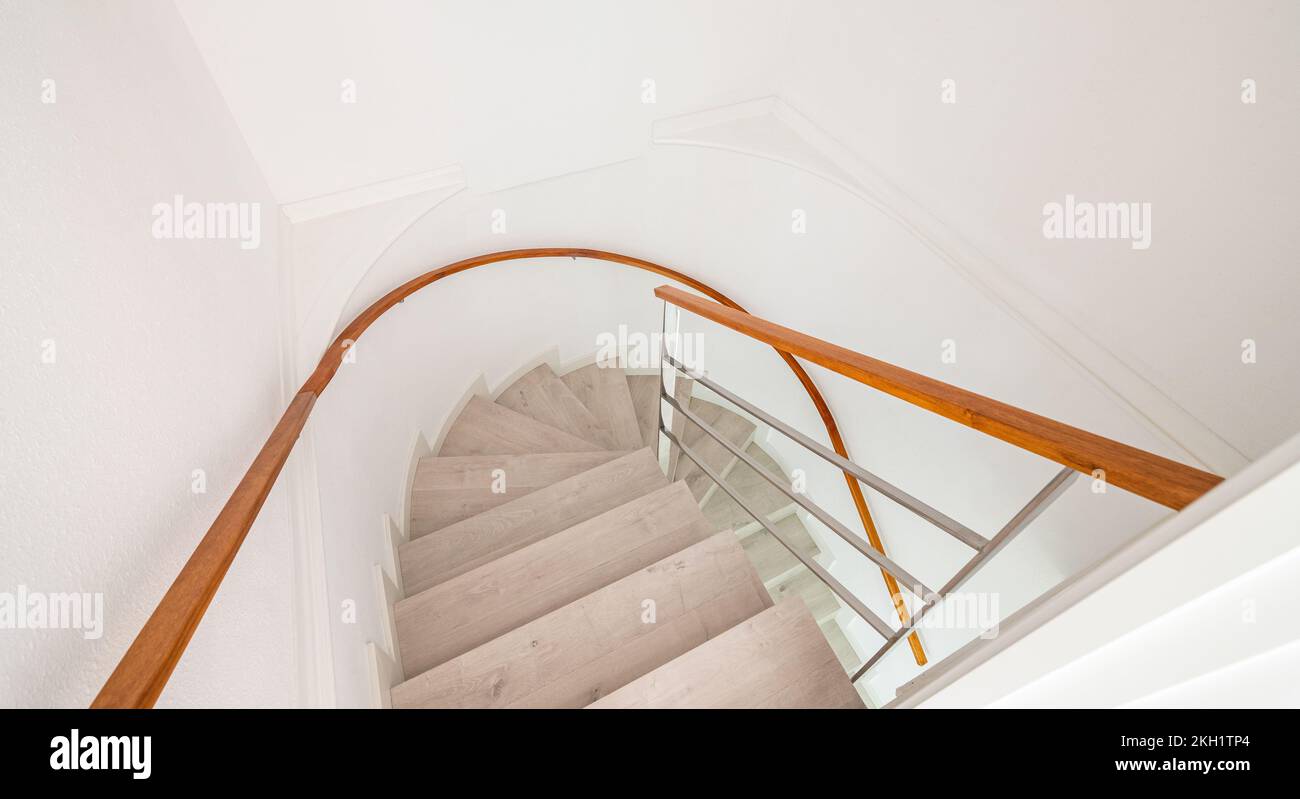 Spiral stairway with white stairs and wooden railing on wall inside of ...