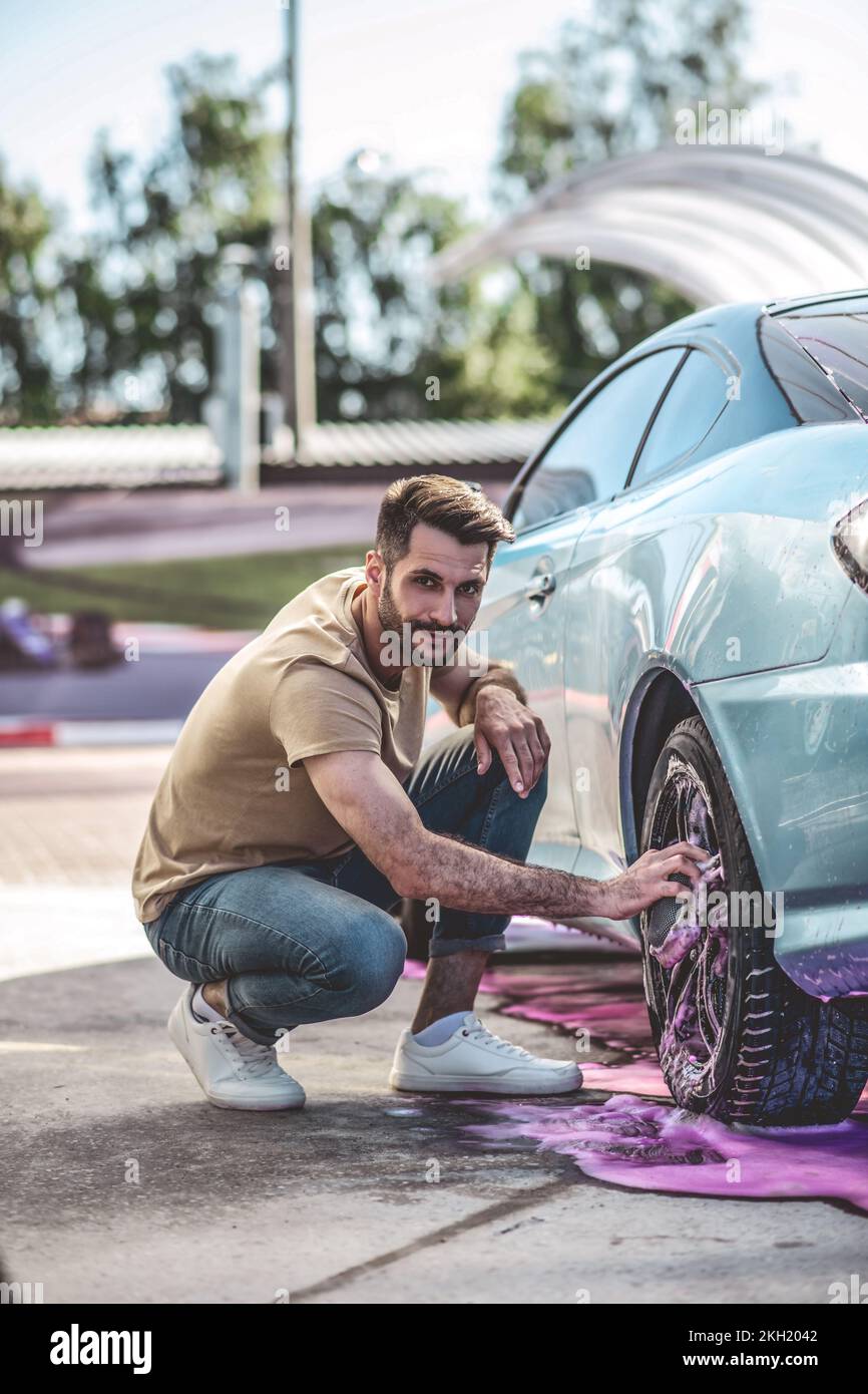 Auto service worker cleaning a motorcar rear wheel Stock Photo - Alamy