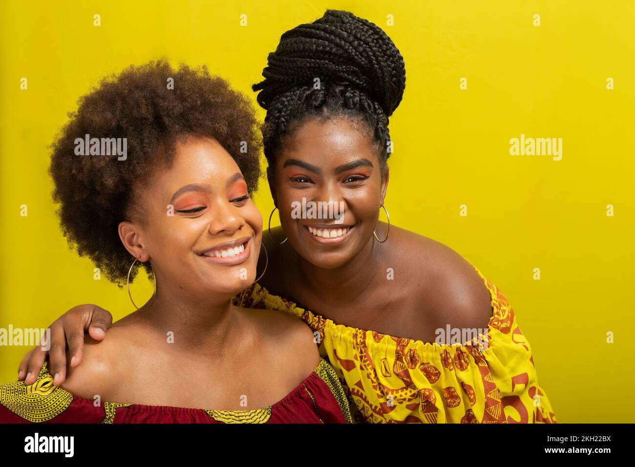 Portrait of two women against yellow background. They wear yellow and ...