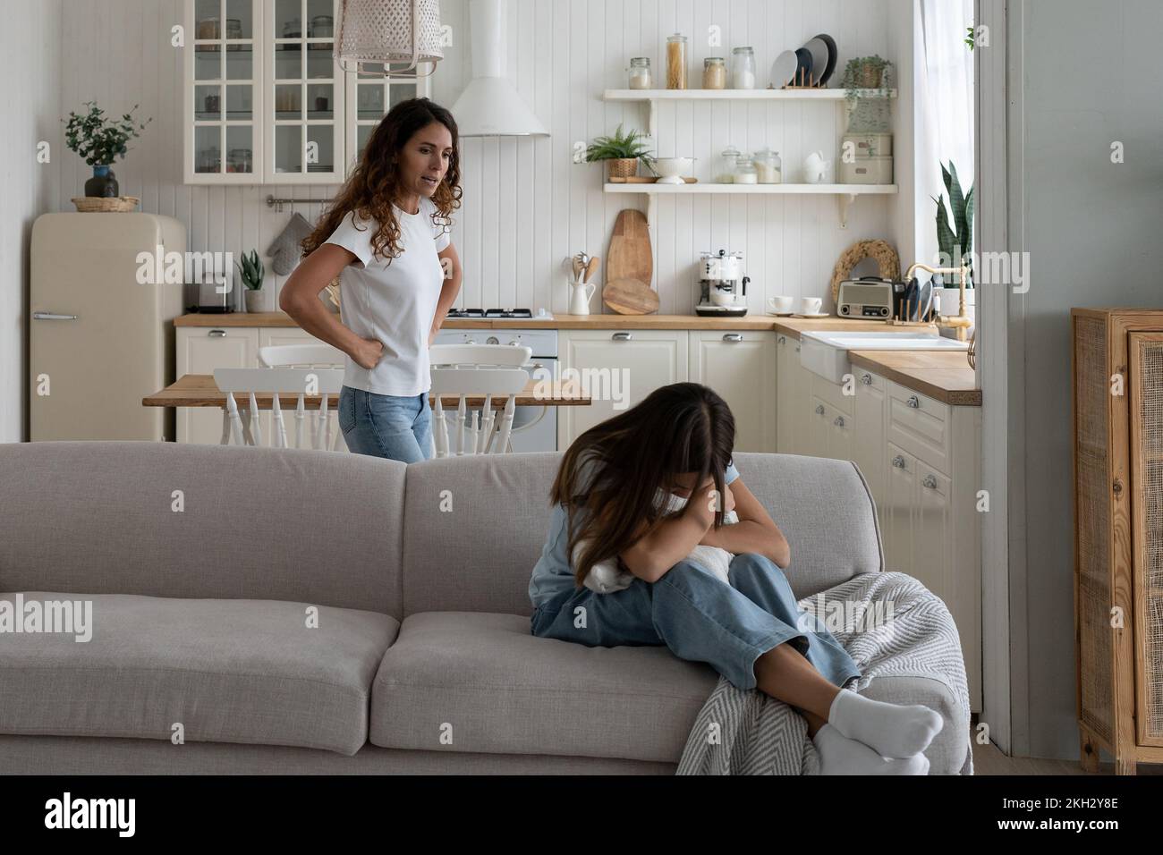 Sad depressed girl daughter sitting on sofa hugging pillow and crying ...