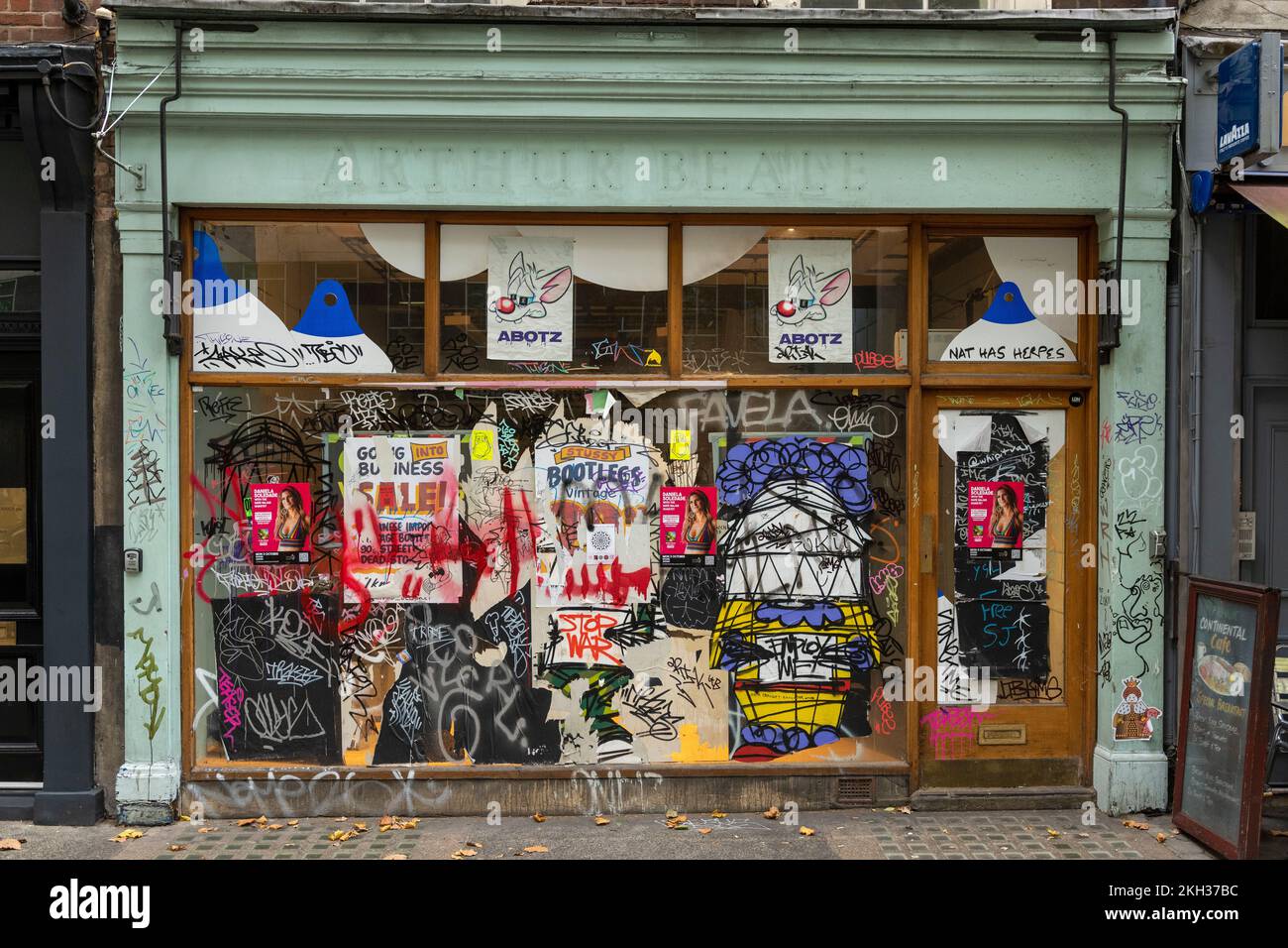 A closed down shop with its windows covered with bill posters and ...