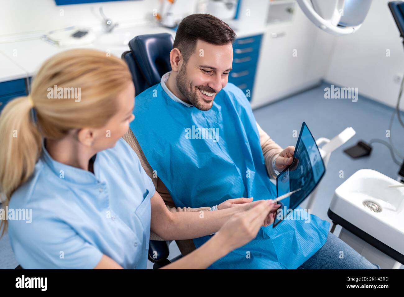 Female dentist pointing at screen with x-ray picture, showing patient ...
