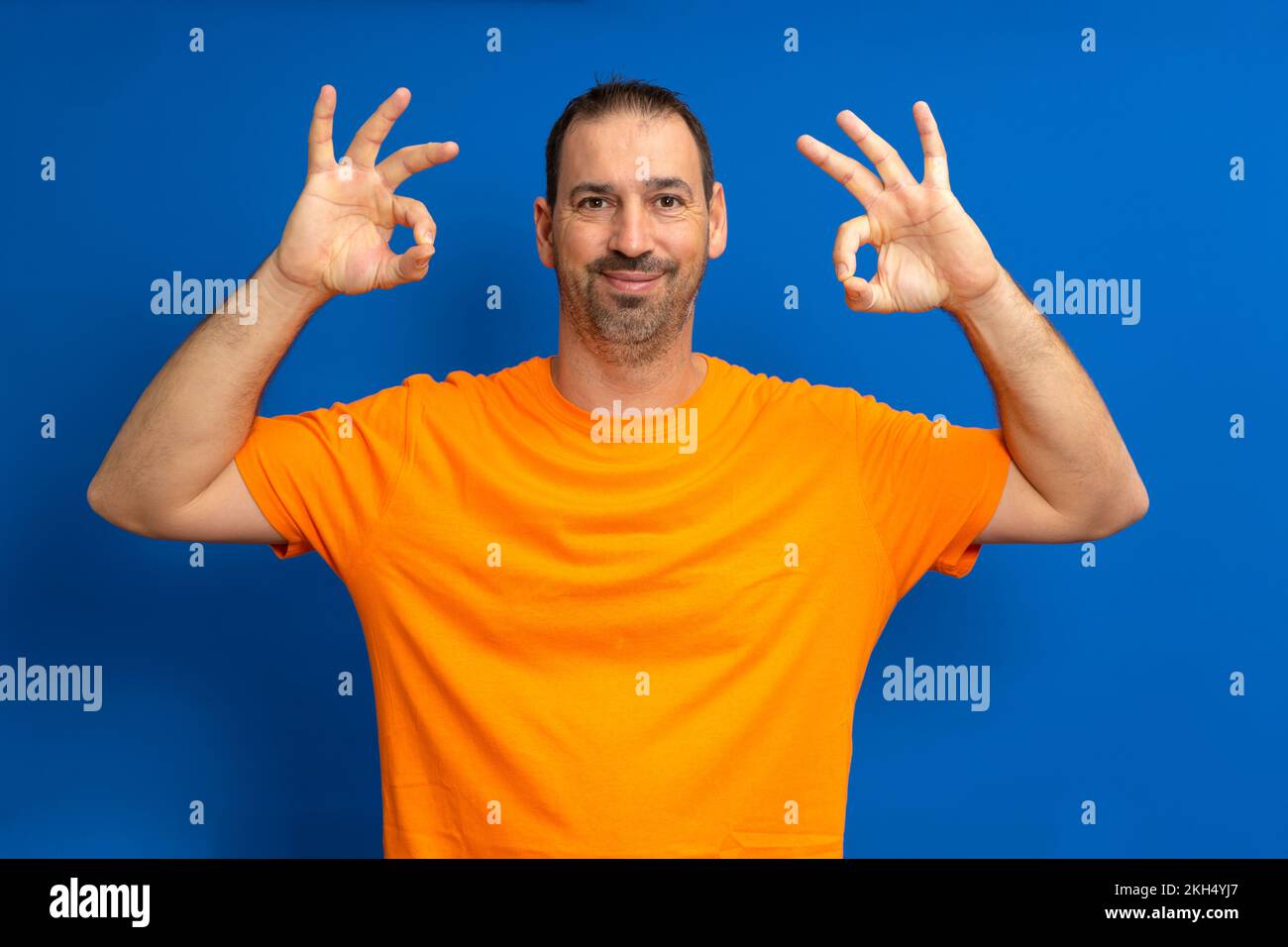 Happy smiling hispanic man with a beard wearing a casual orange t-shirt ...