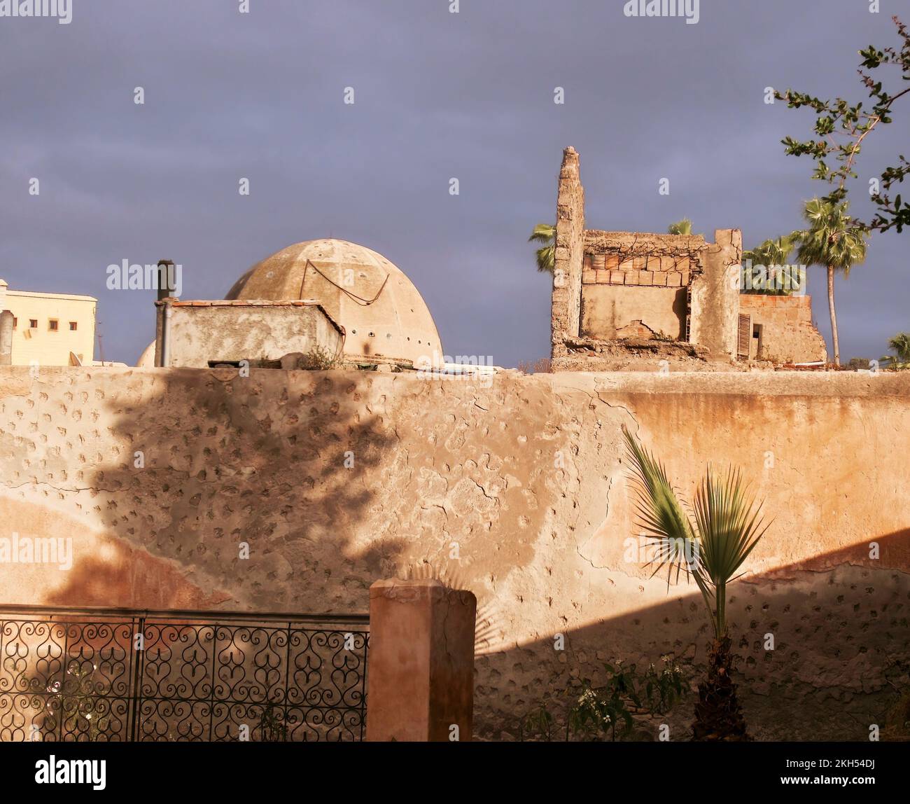 Stone wall of the Medina, with dome beyond and dark, grainy sky and ...