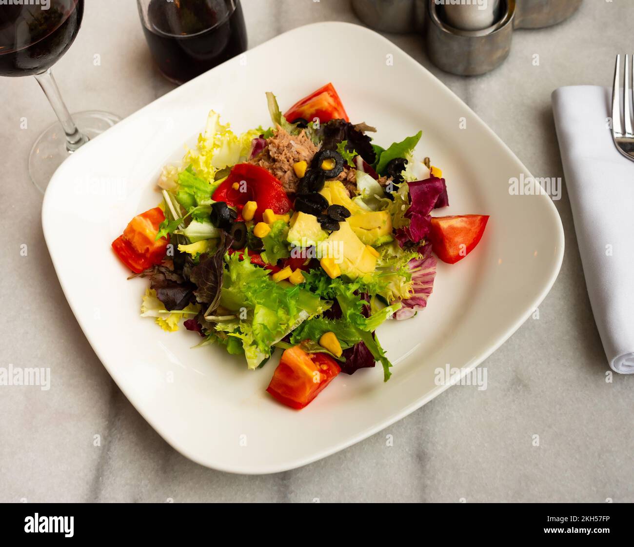 Salad with tuna, roasted peppers and avocado in a deep square plate ...