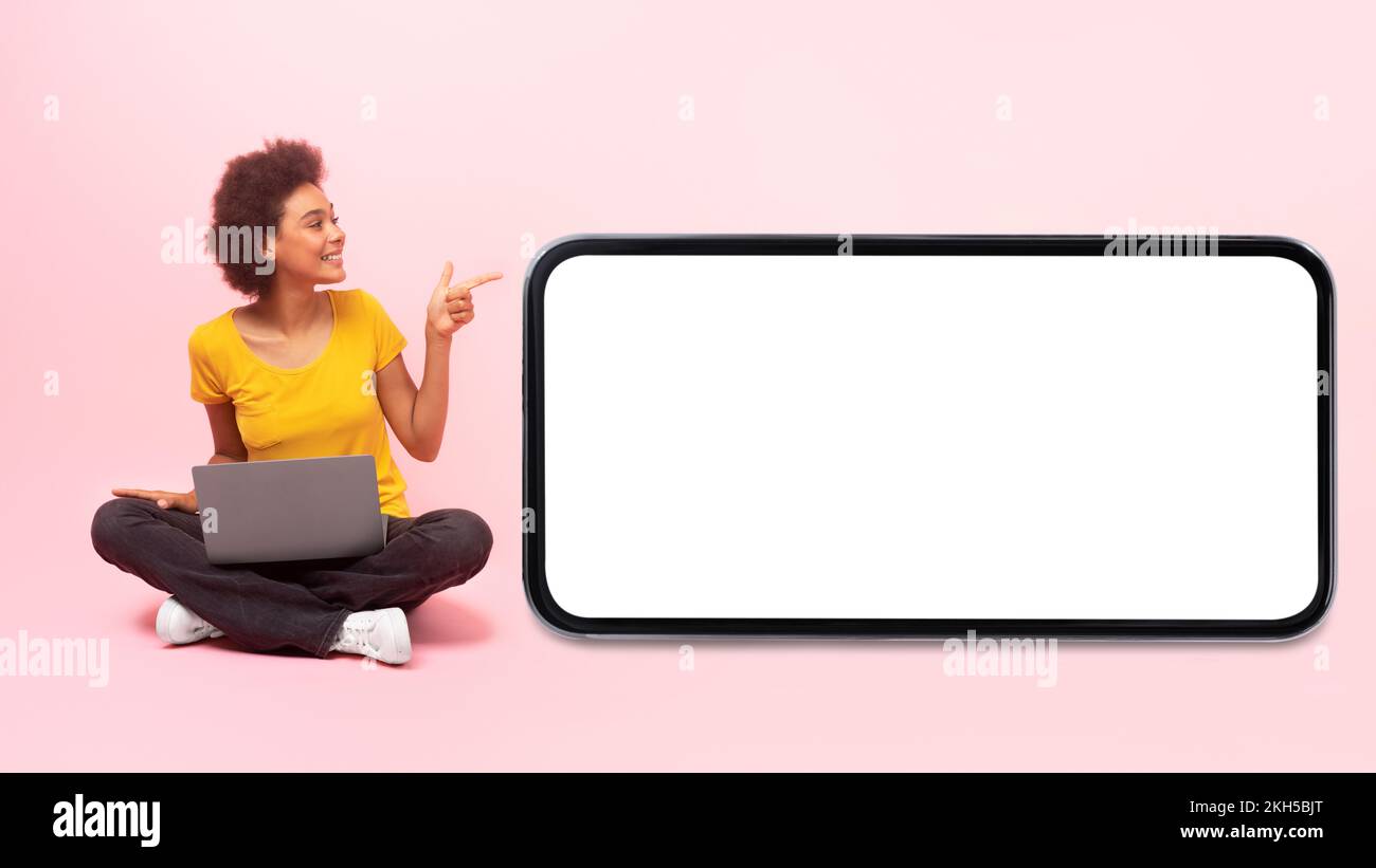 Smiling millennial african american curly lady sit on floor with laptop ...