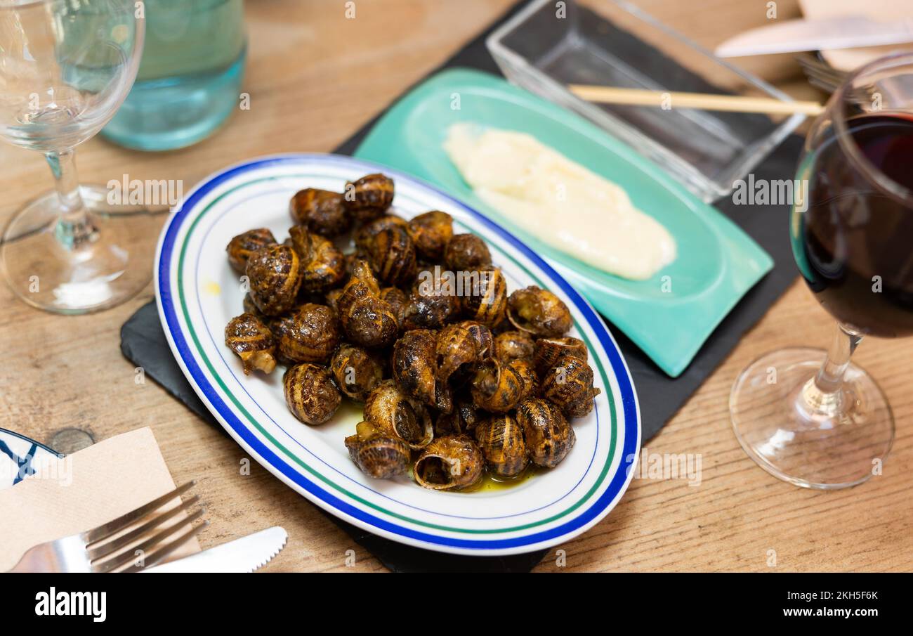 Plate of Caracoles cooked in shells on grill aioli sauce Stock Photo ...