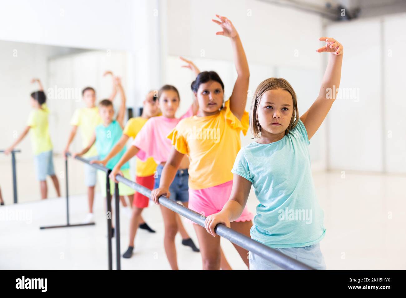 Children standing along ballet bar in dance studio during dance class ...