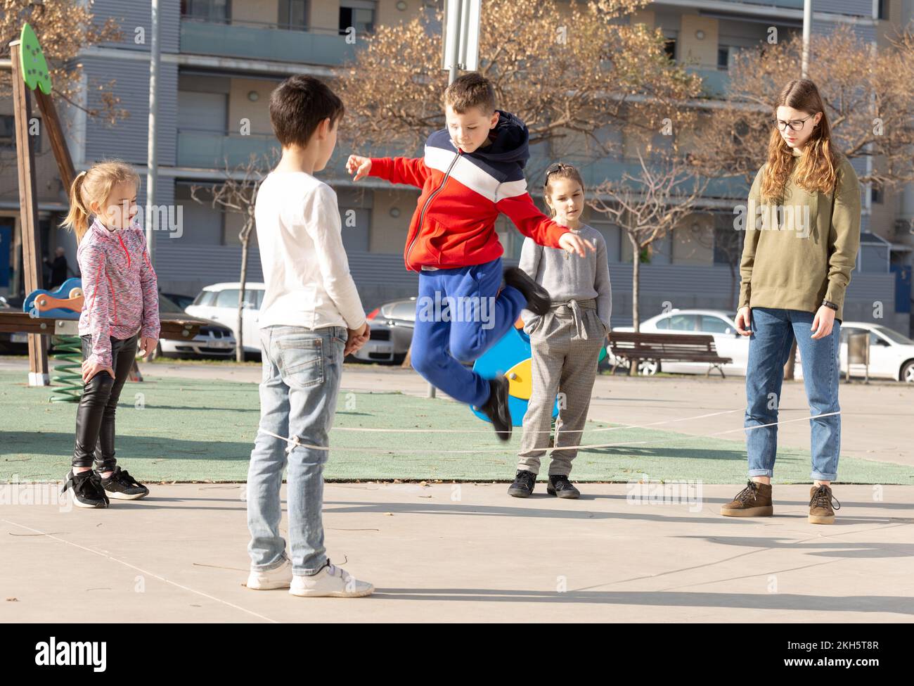 Happy smiling little friends playing with chinese jumping rope at ...