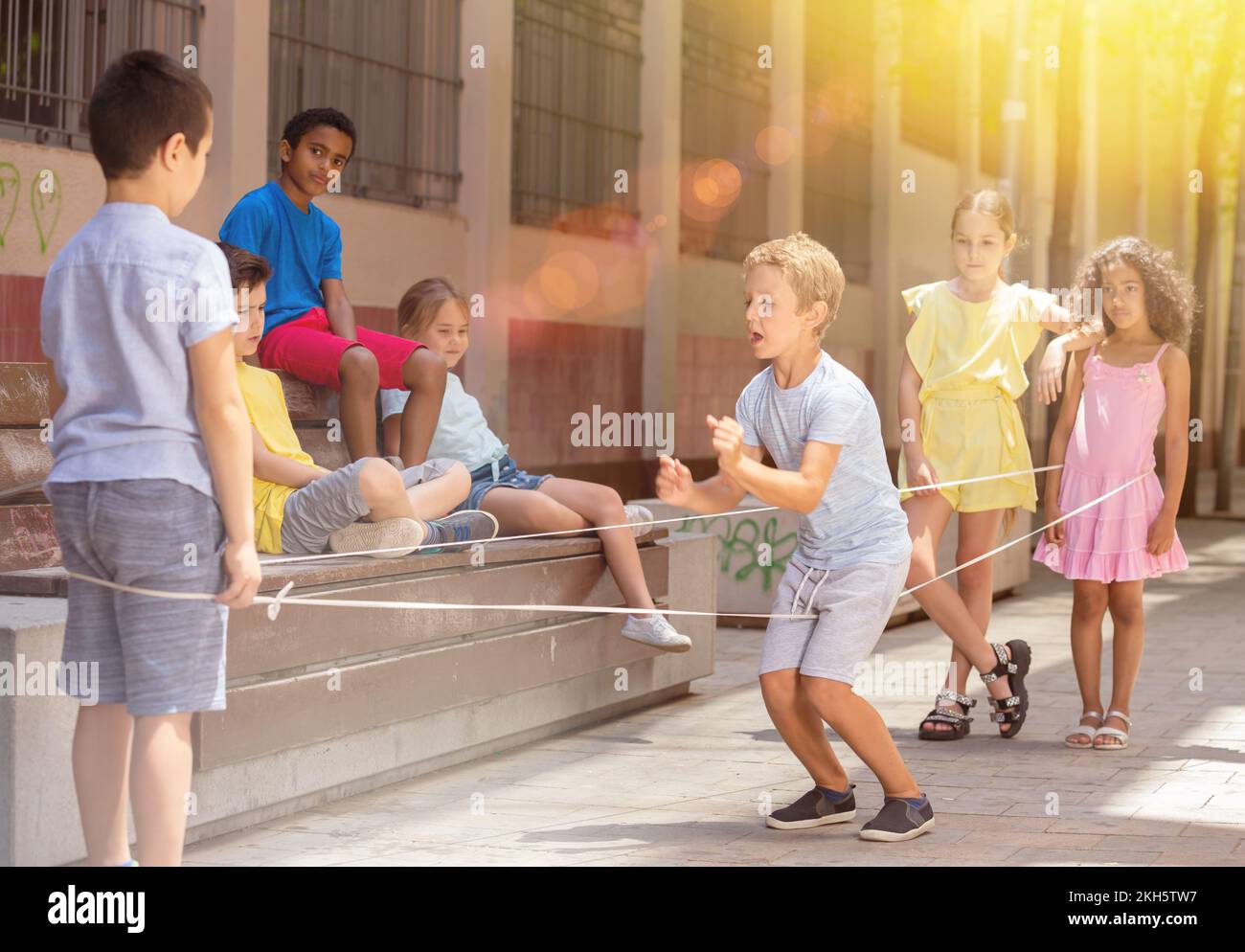 Little boy jumping on rubber band with friends in historical center ...