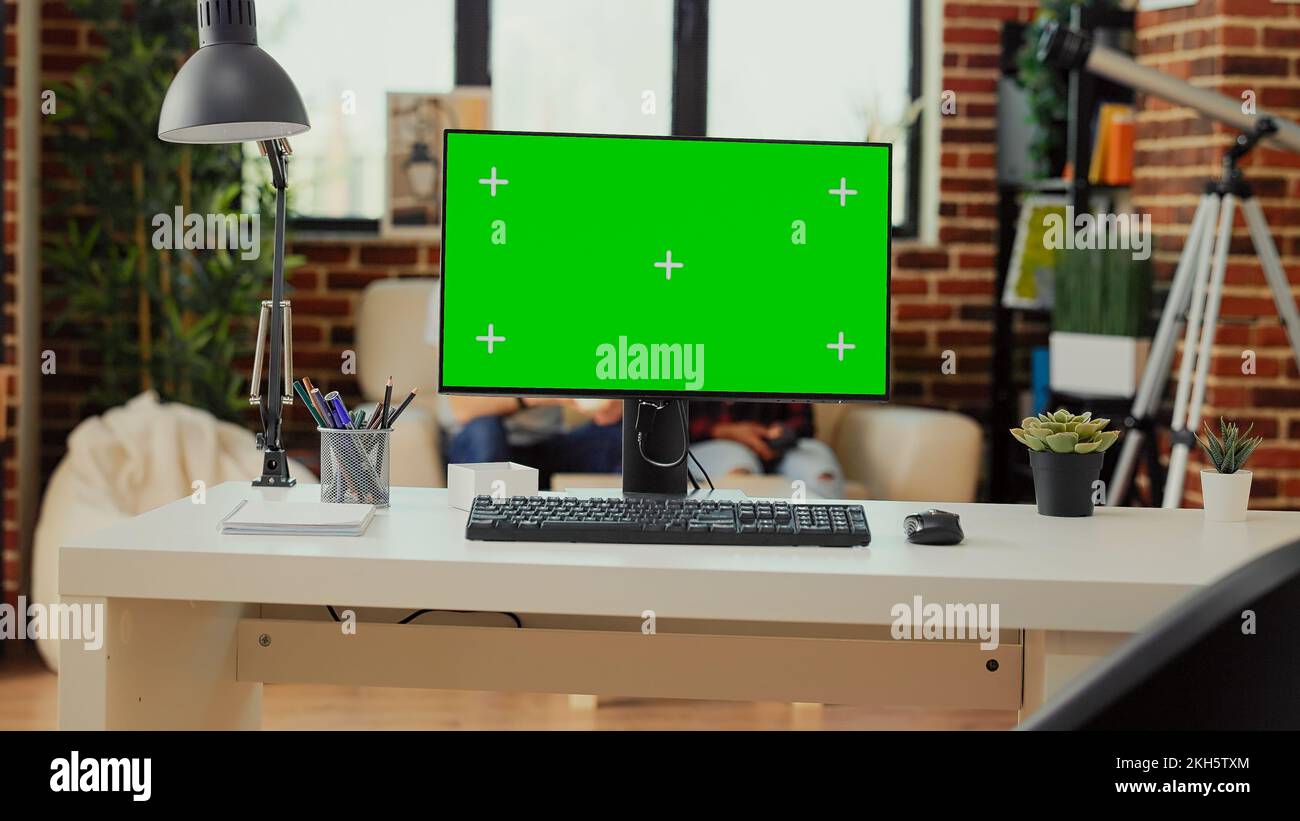 Empty office desk with greenscreen display on computer used to work on freelance in living room ...