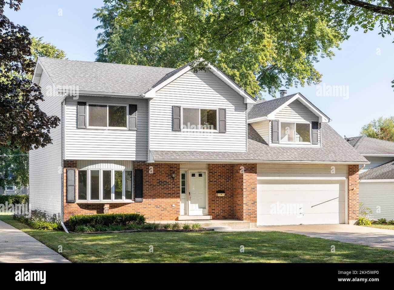 A suburban home with vinyl siding and red brick and a two car garage ...