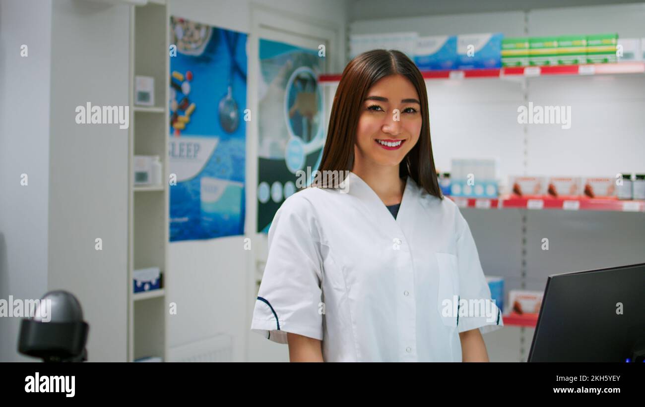 Happy asian pharmacist working at drugstore counter, examining ...