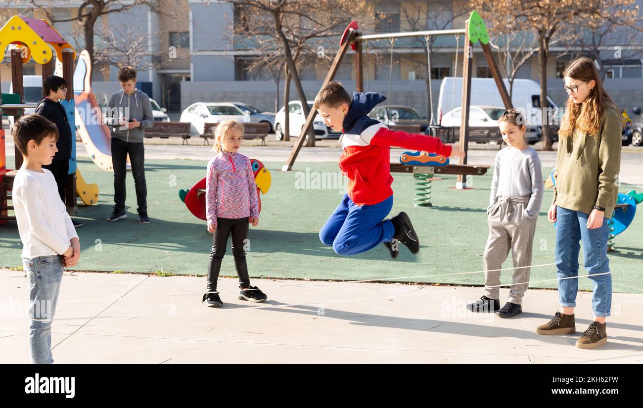 Happy smiling little friends playing with chinese jumping rope at ...