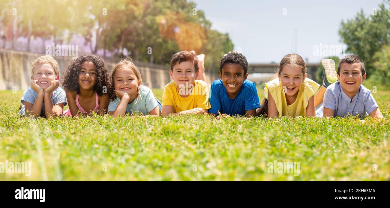 Group of school children resting on grass and smiling Stock Photo - Alamy