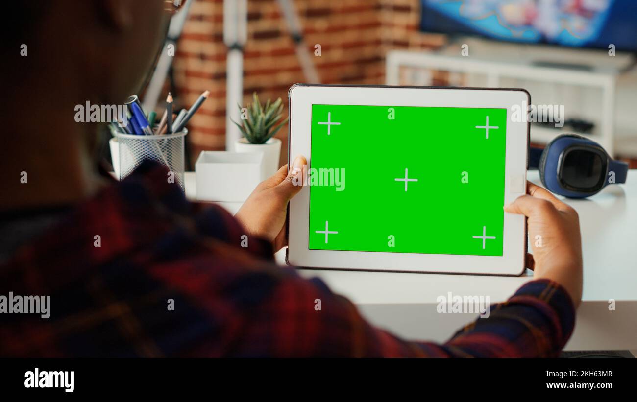 Female freelancer holding digital gadget with horizontal green screen ...