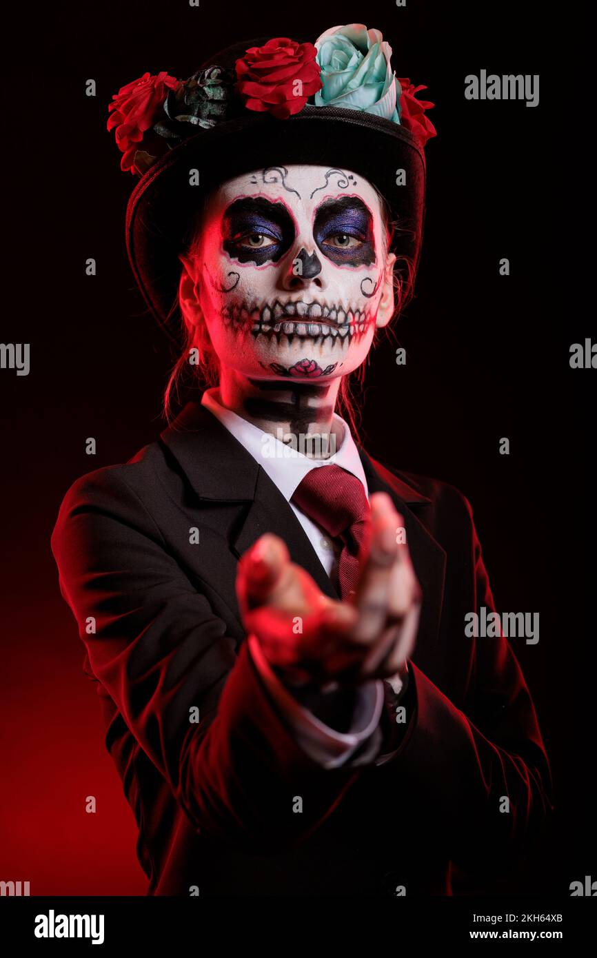 Flirty woman reaching with hand to lure people, wearing skull make up ...