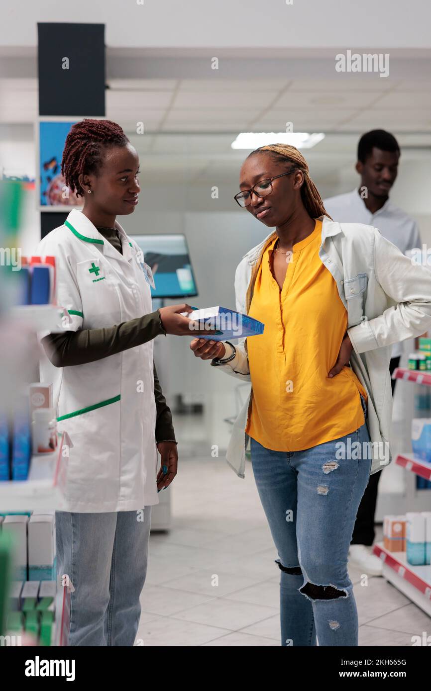 Customer buying back pain medication in drugstore, pharmacy consultant and buyer talking ...