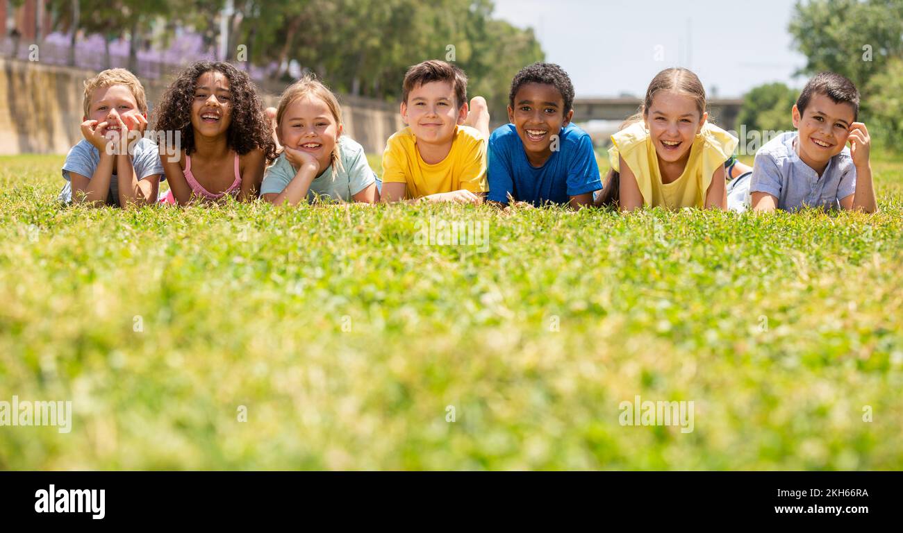 Group of school children resting on grass and smiling Stock Photo - Alamy