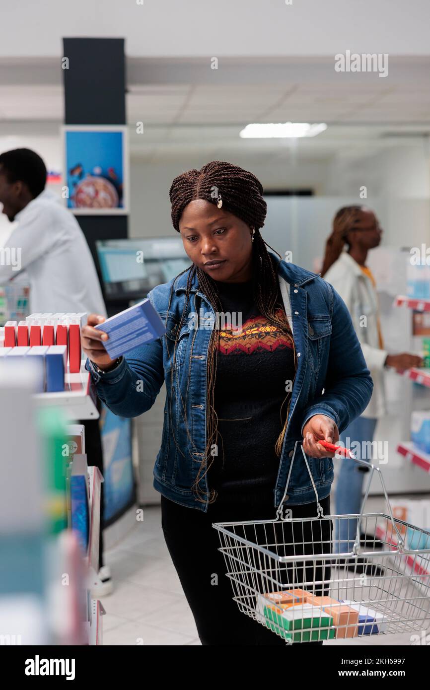 African american customer buying medication in pharmacy, reading ...