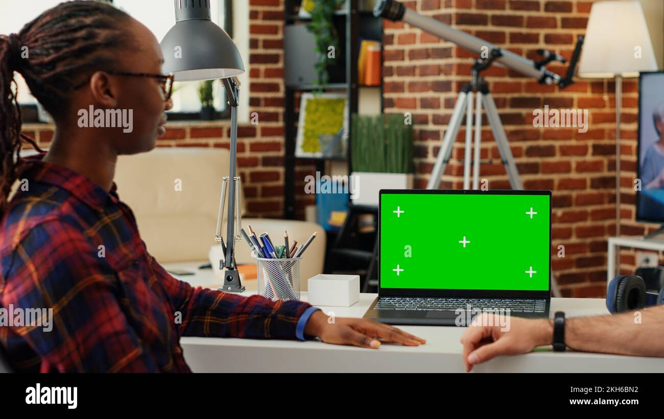 Multiethnic team of man and woman analyzing greenscreen display on ...