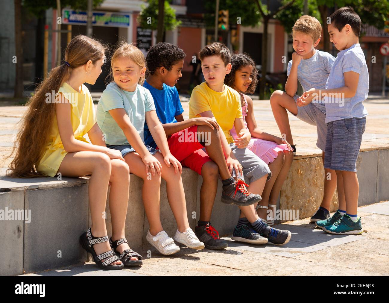 Positive children chatting together sitting at urban street Stock Photo ...