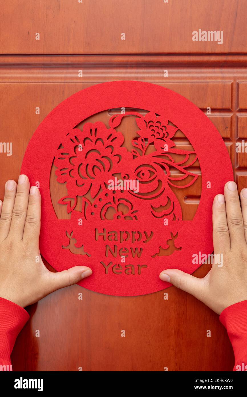 man sticking a Chinese New Year of Rabbit paper cut decoration to a ...