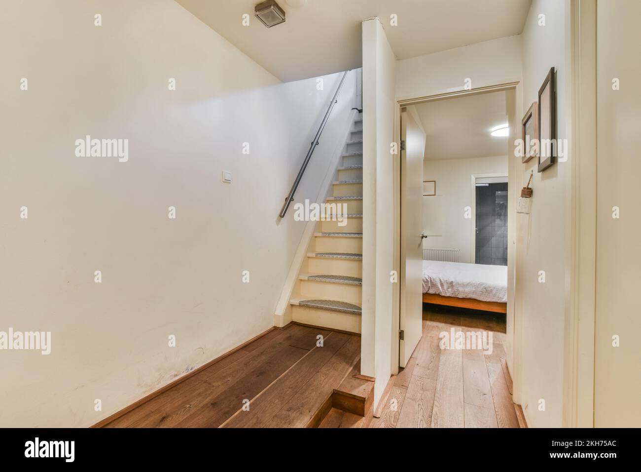 White hallway with wooden stairway leading to second floor of apartment ...