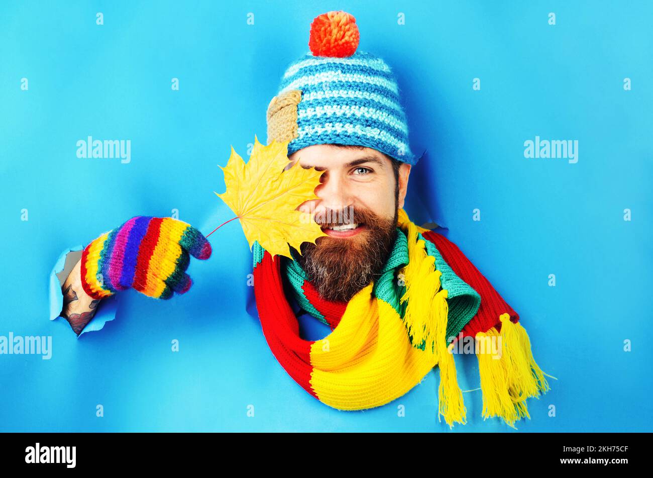 Smiling bearded man in knitted hat, scarf and gloves covered eye with ...