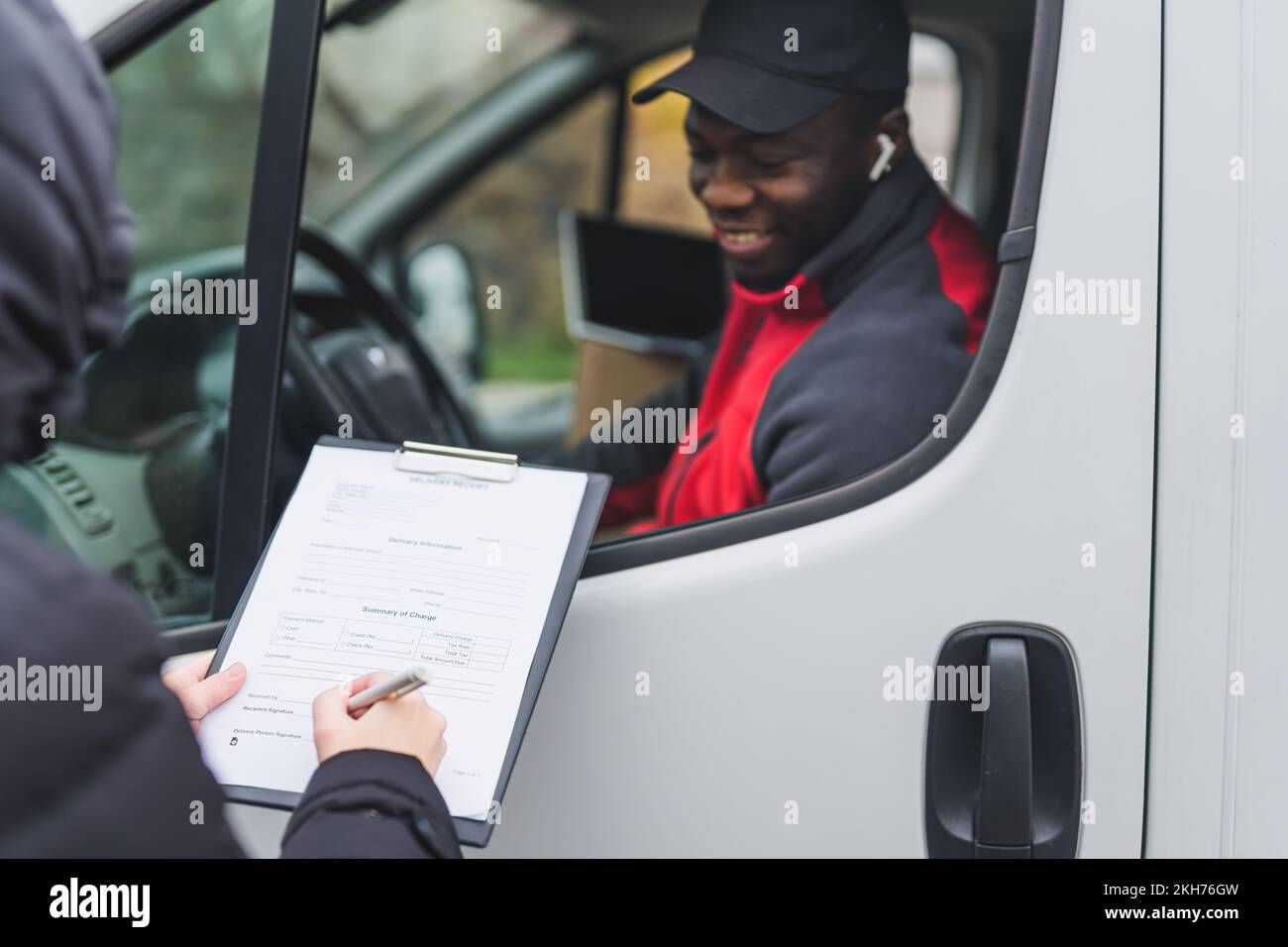 Young adult black delivery man sitting inside white van looking outside ...