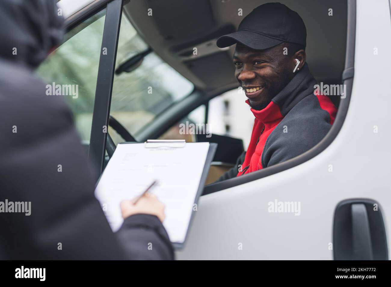 Happy positive Black courier joking around with unrecognizable person ...