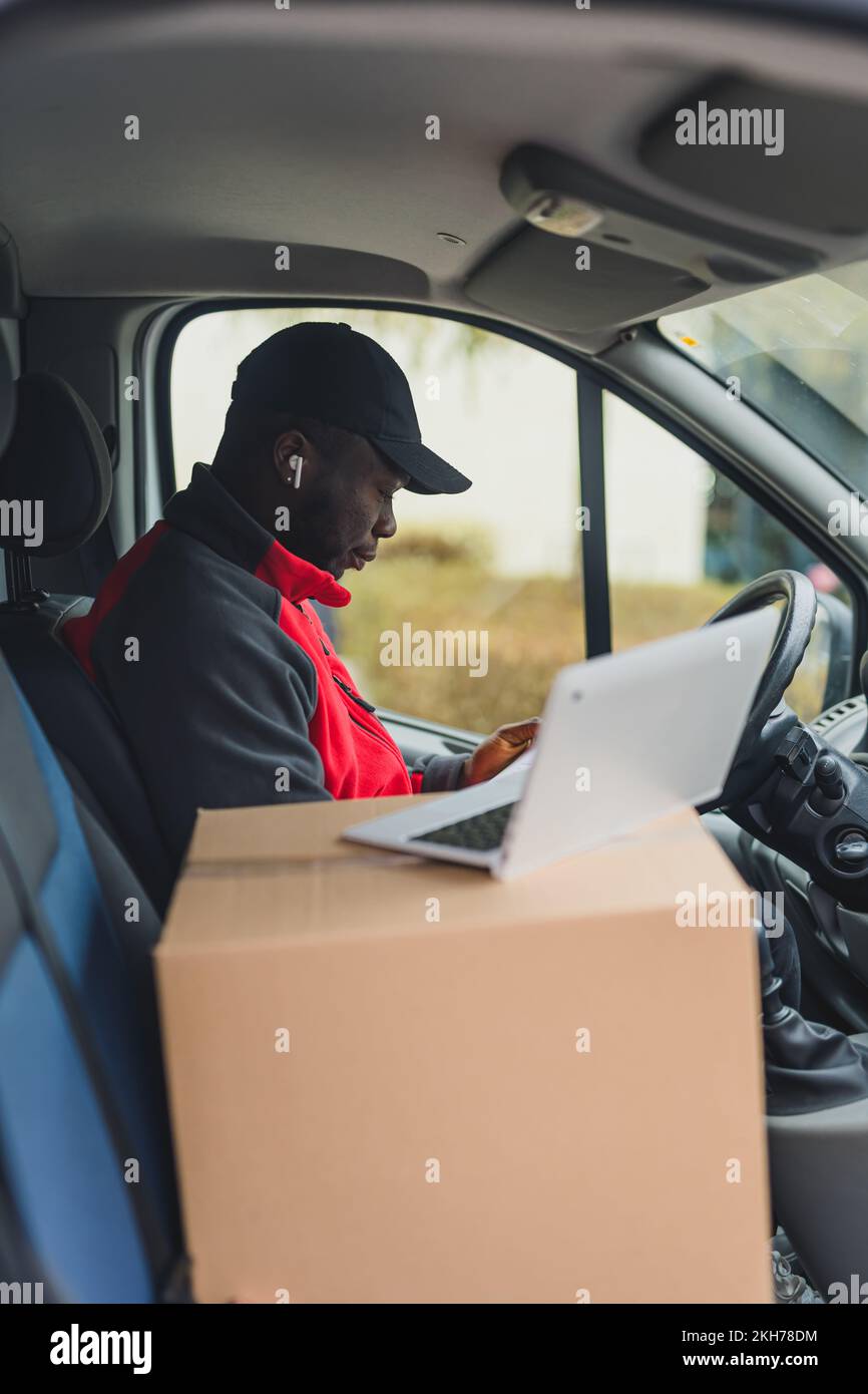 Vertical in-car shot of focused Black middle-aged man in black hat and ...