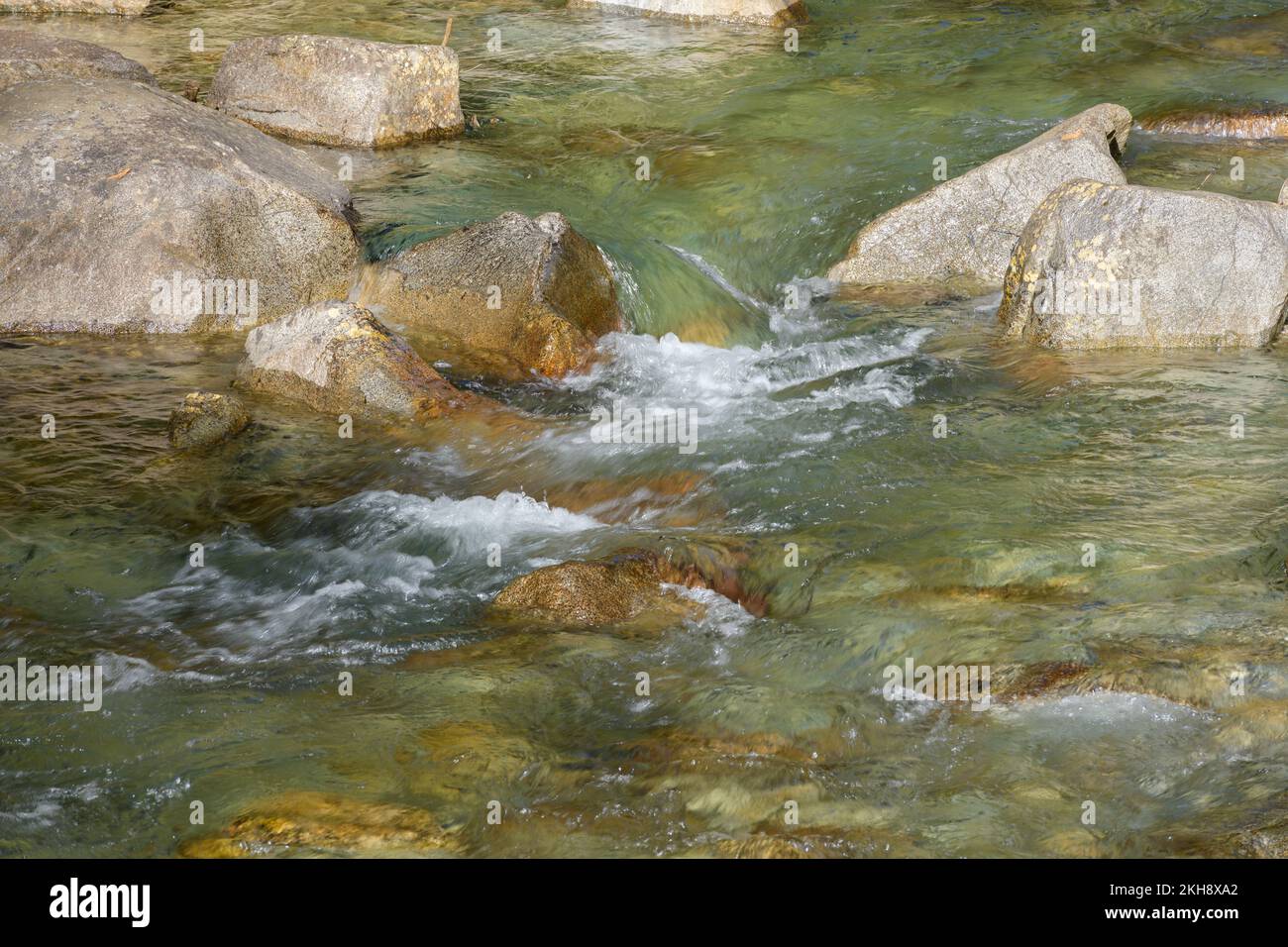 Mountain stream flowing between rough river rocks on a diagonal path in ...