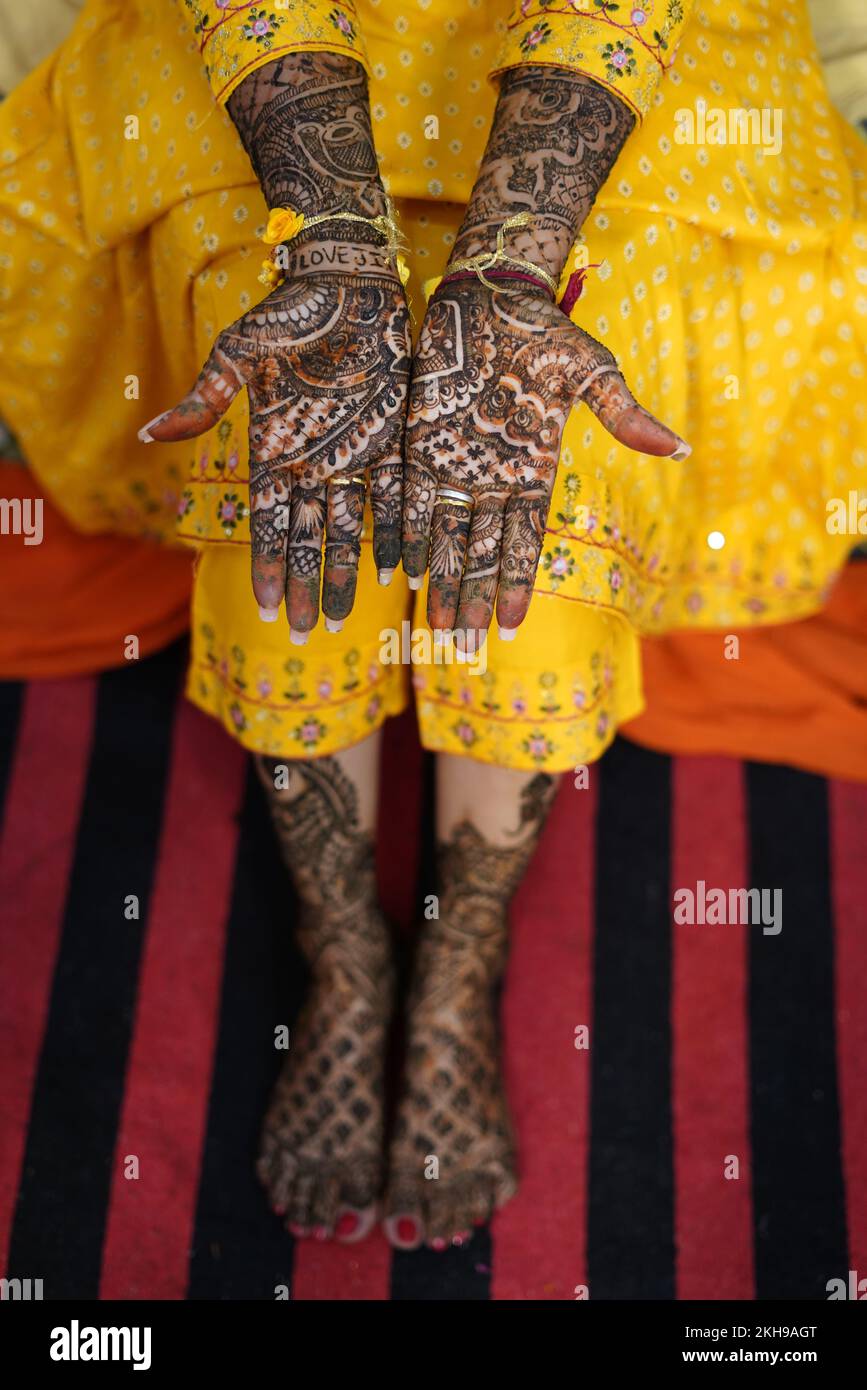 A vertical image of a female in yellow dress showing wedding henna ...