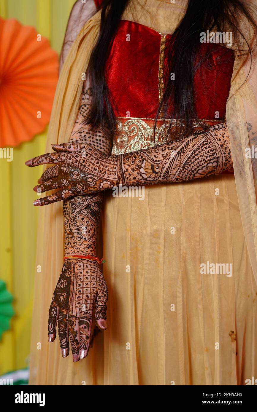 A vertical image of a female in yellow dress showing wedding henna ...