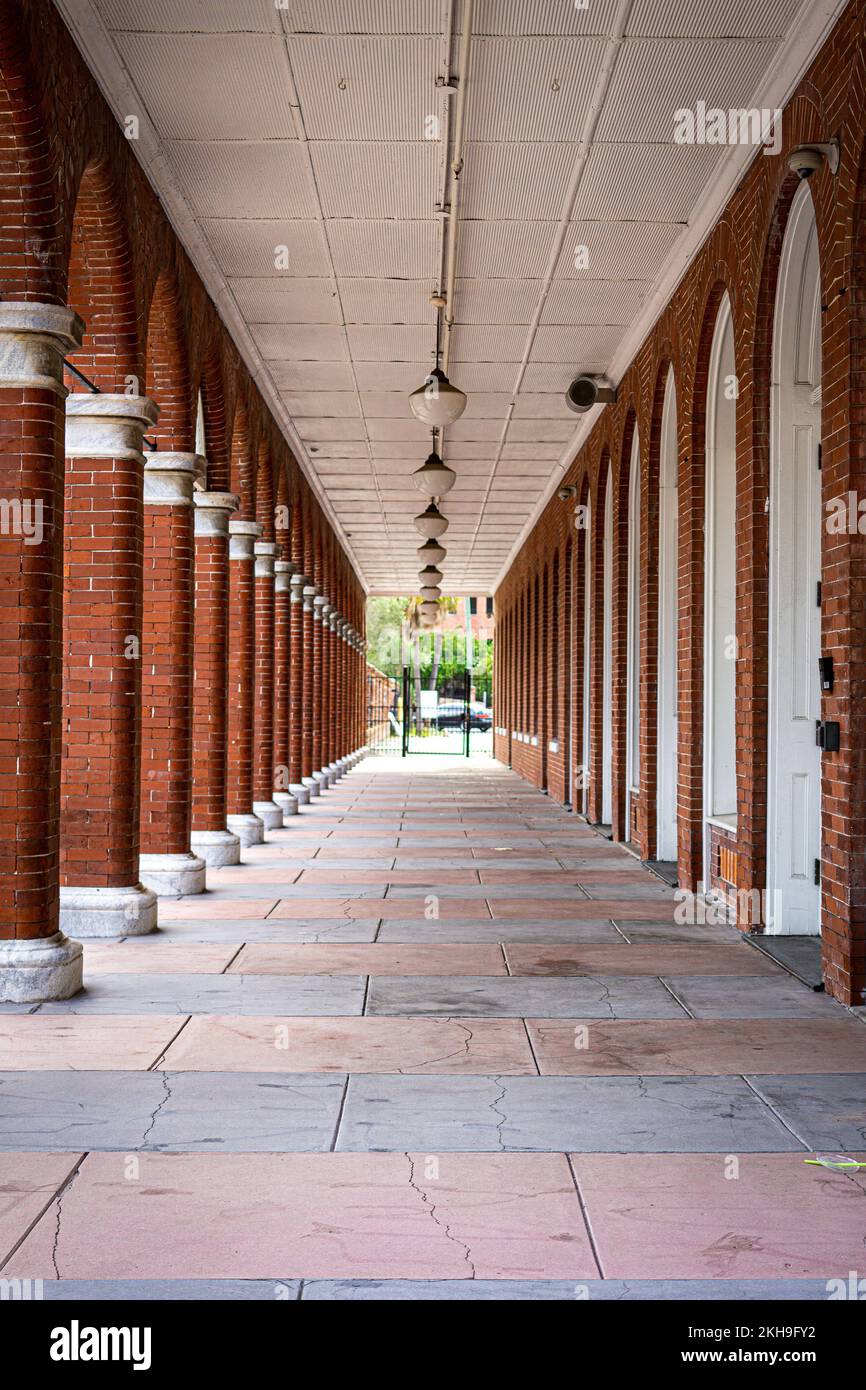 A vertical shot through an arched walkway with brick wall and columns ...