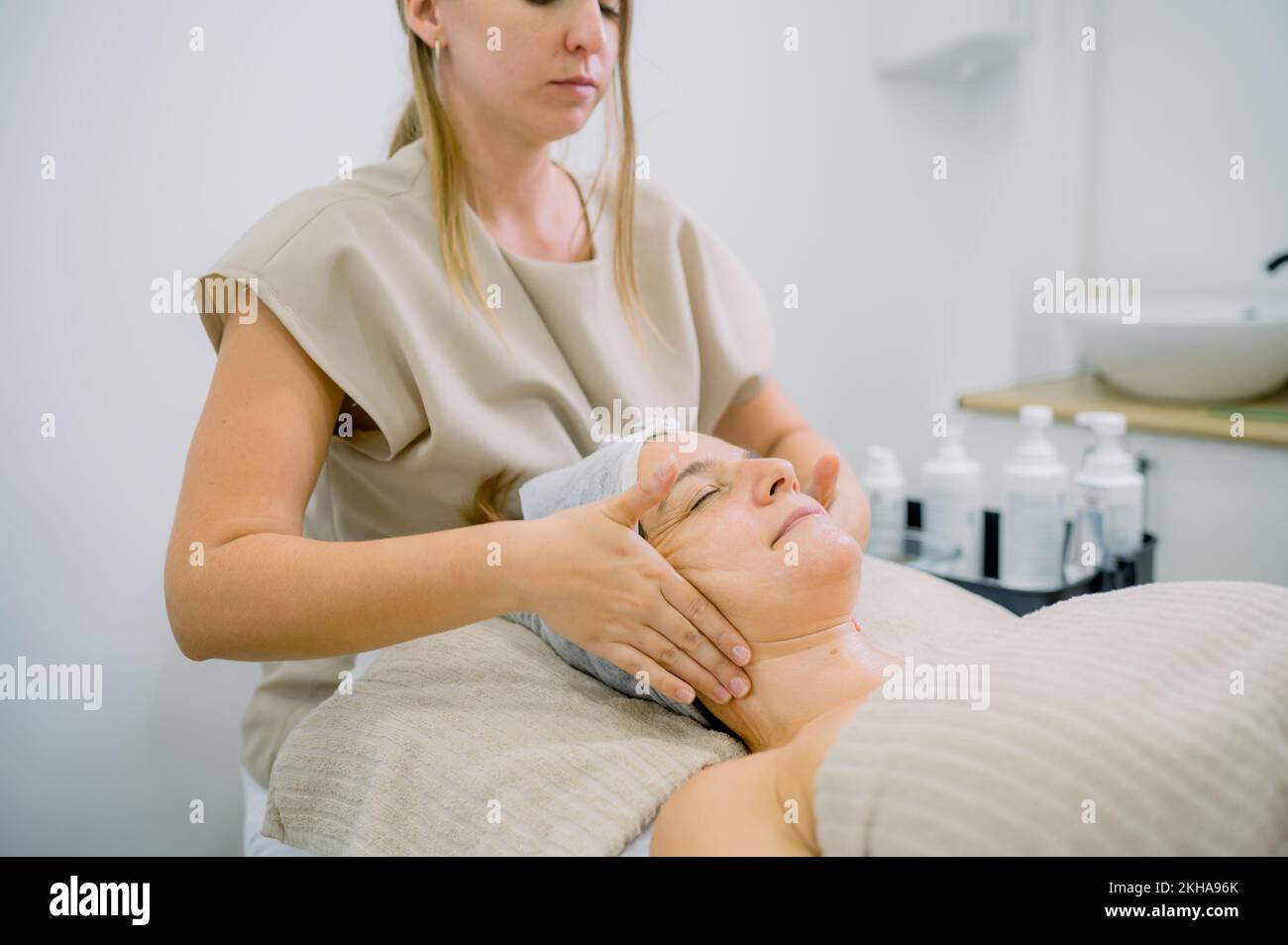Crop beautician rubbing face of woman Stock Photo - Alamy