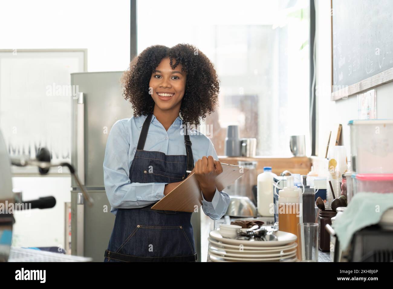 Portrait of a smiling young african american waitress wearing apron ...