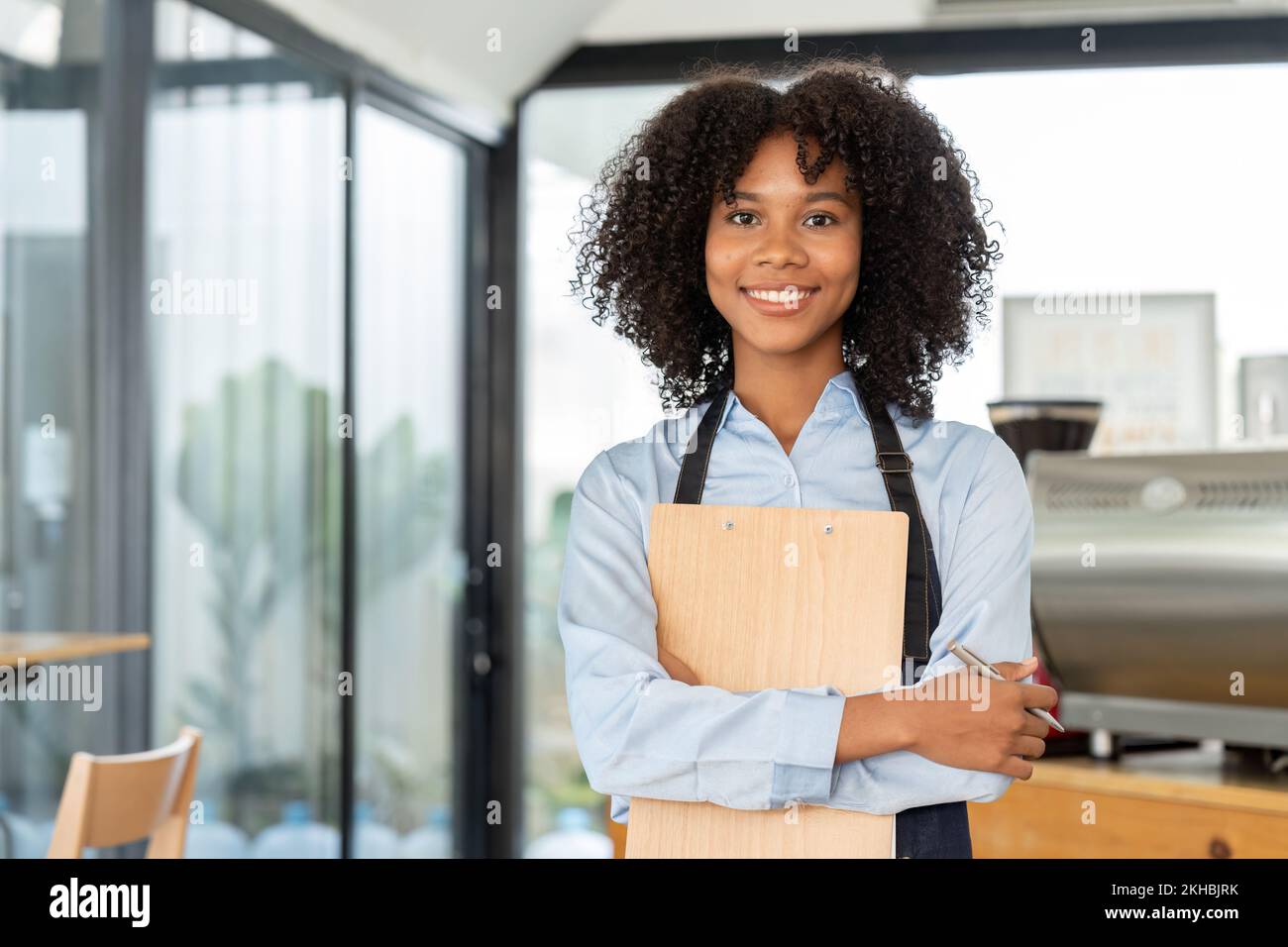 Portrait of a smiling young african american waitress wearing apron ...