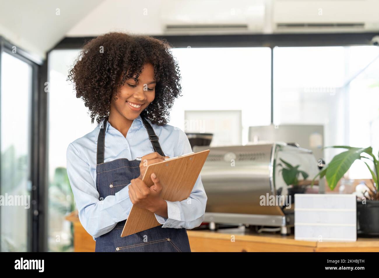 Portrait of a smiling young african american waitress wearing apron ...