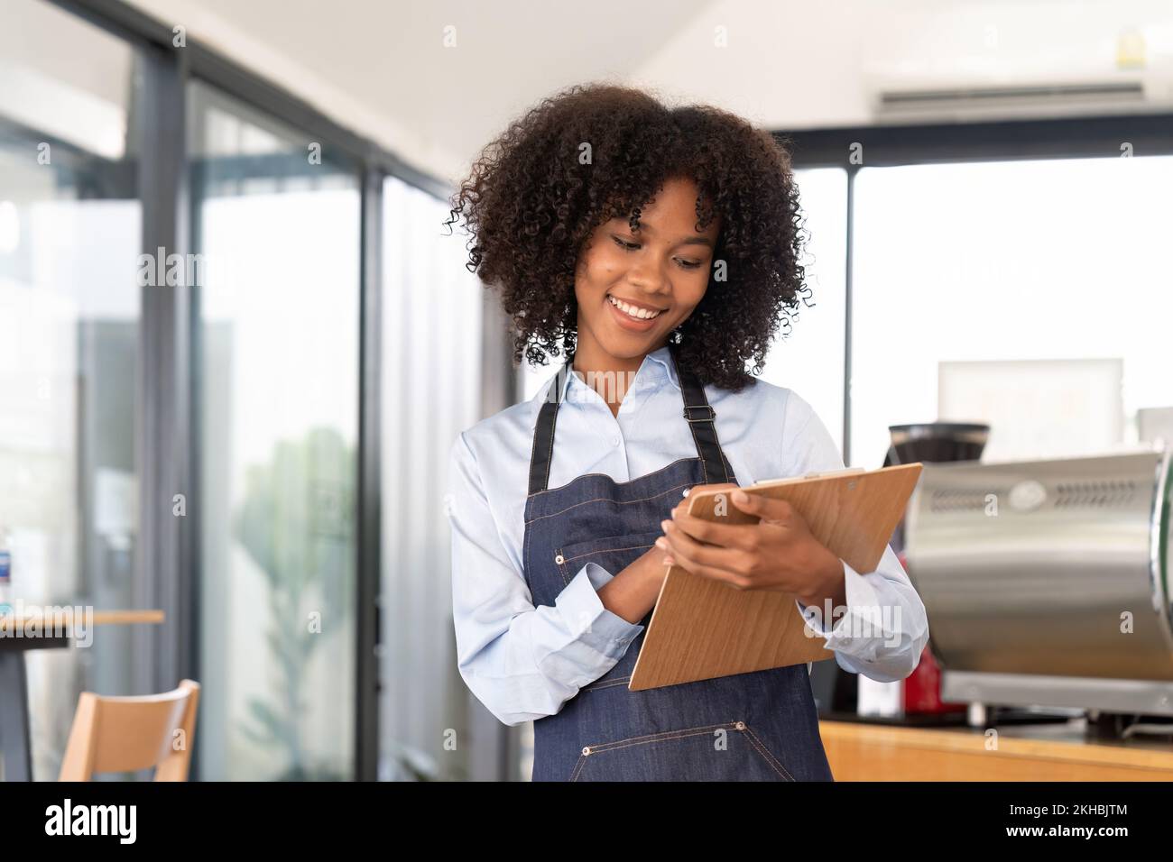 Portrait of a smiling young african american waitress wearing apron ...